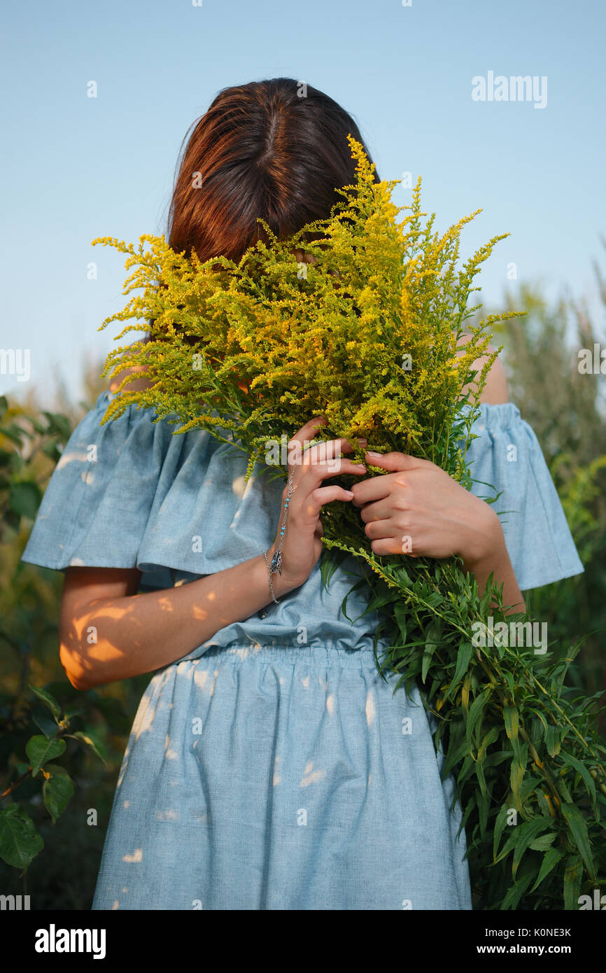 Pretty girl hiding face in field flowers Stock Photo - Alamy