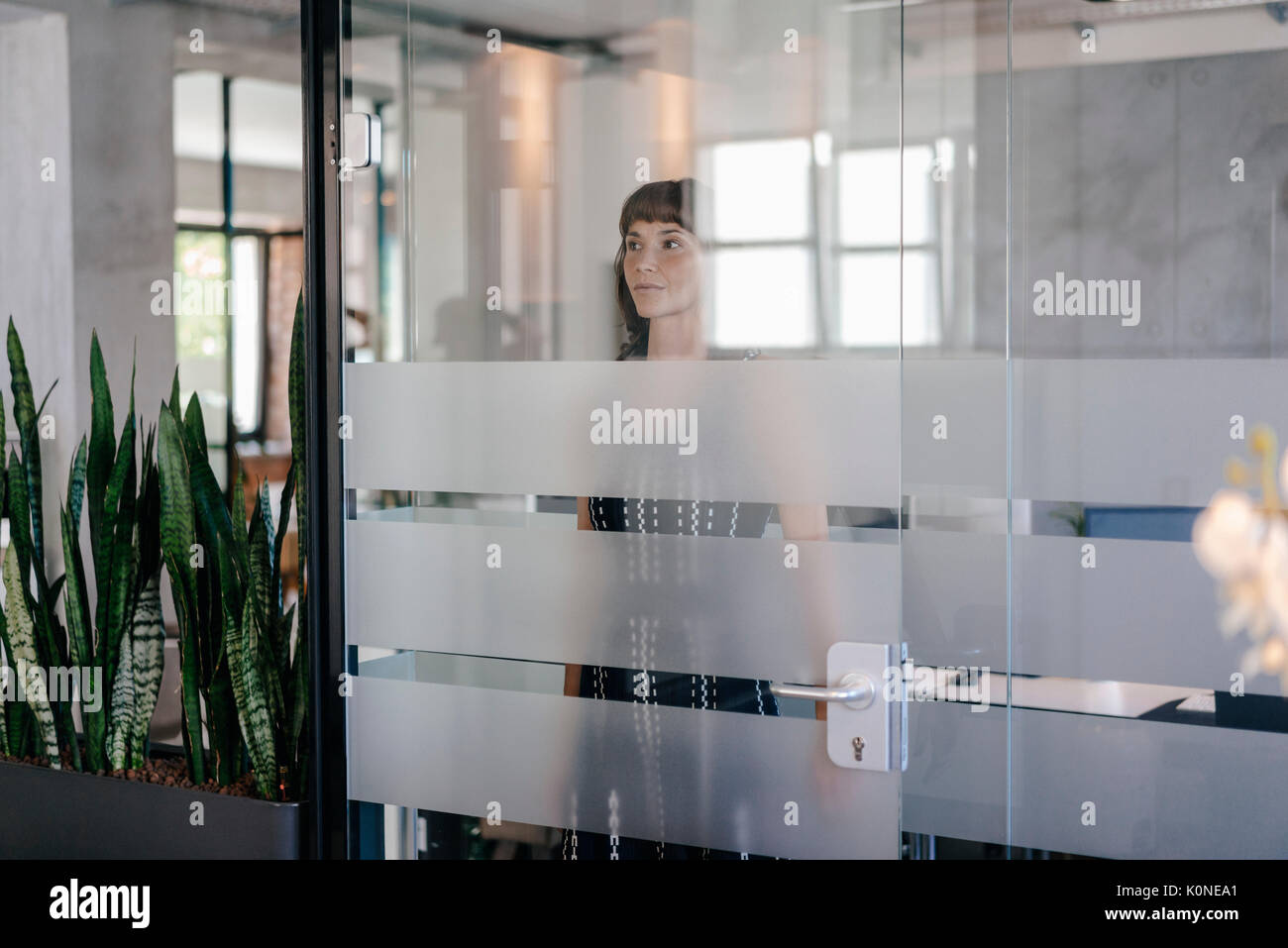 Businesswoman standing behind glass door Stock Photo - Alamy