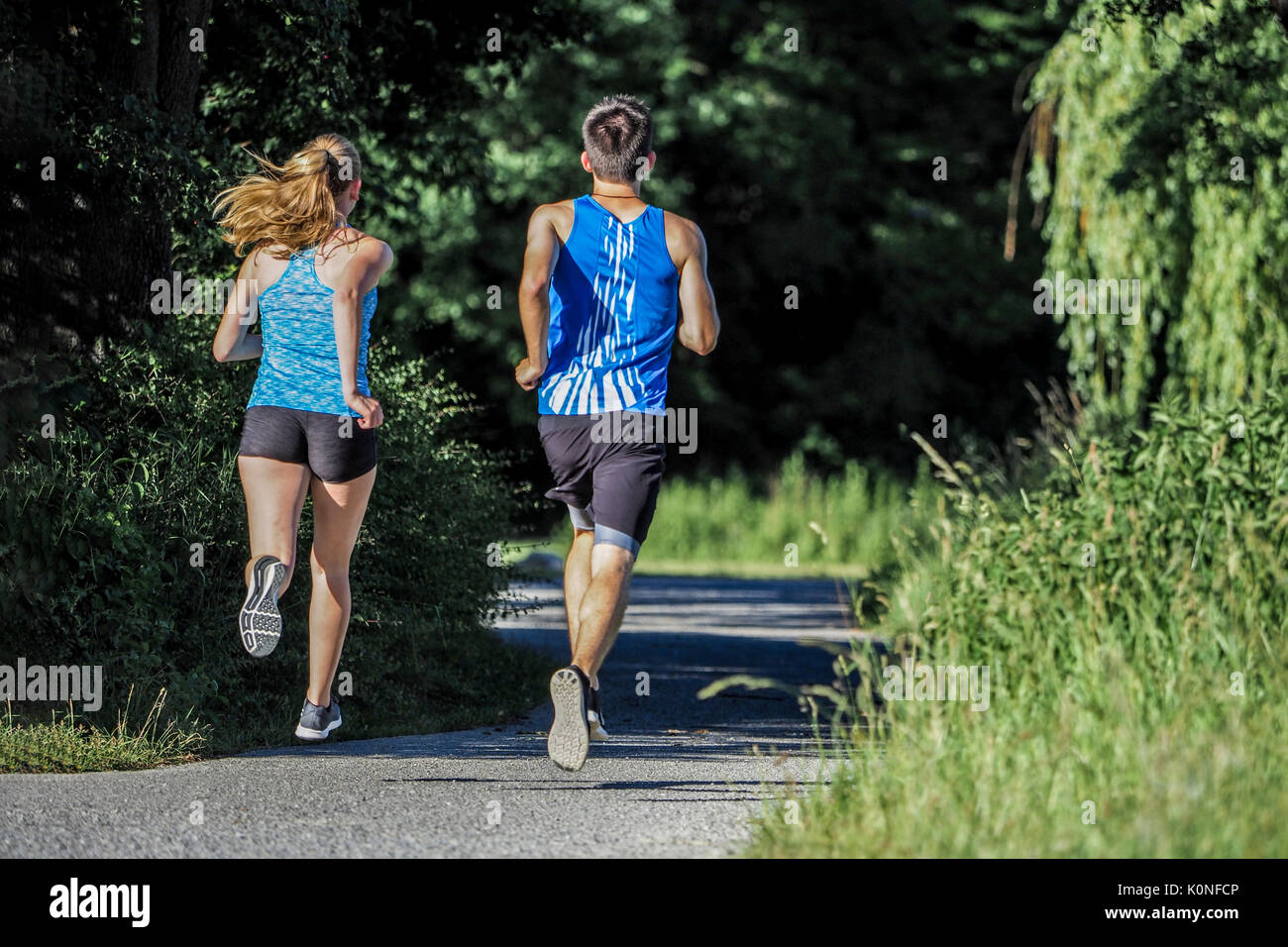 Back view of young couple jogging in park Stock Photo - Alamy