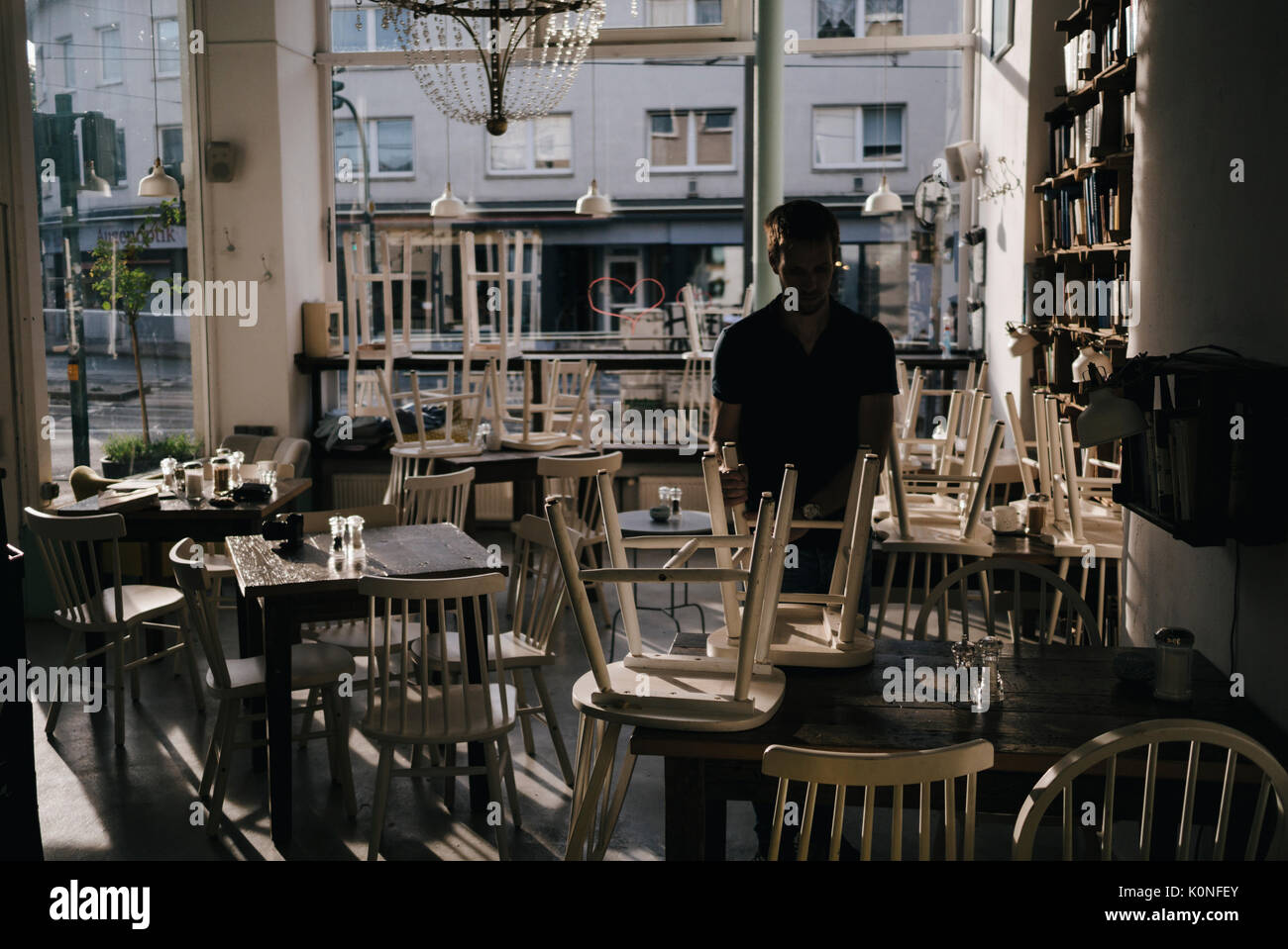 Man clearing cafe at closing time Stock Photo - Alamy