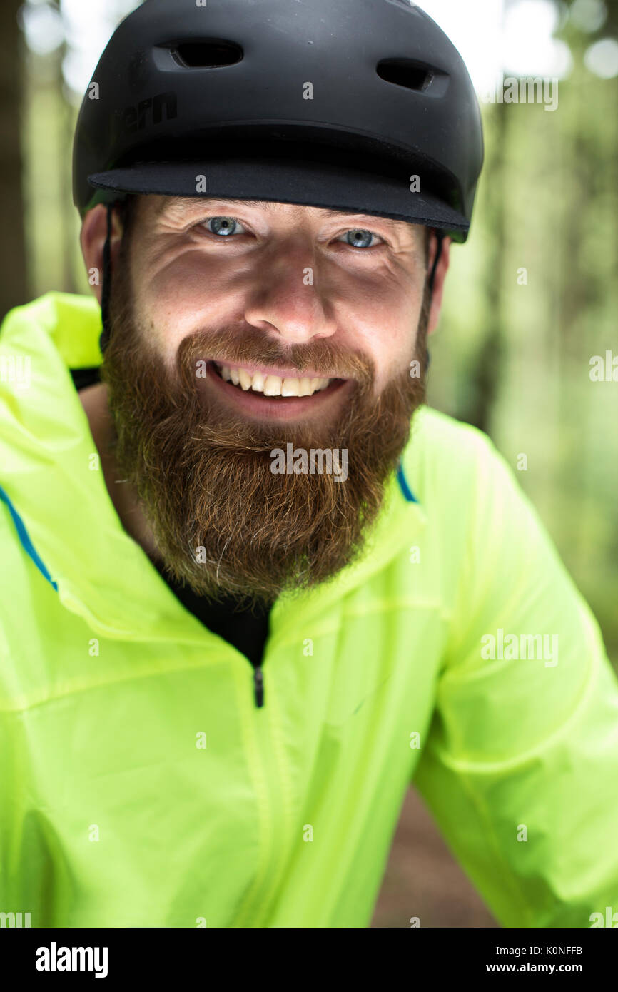 Portrait of smiling man with full beard wearing black cycling helmet ...