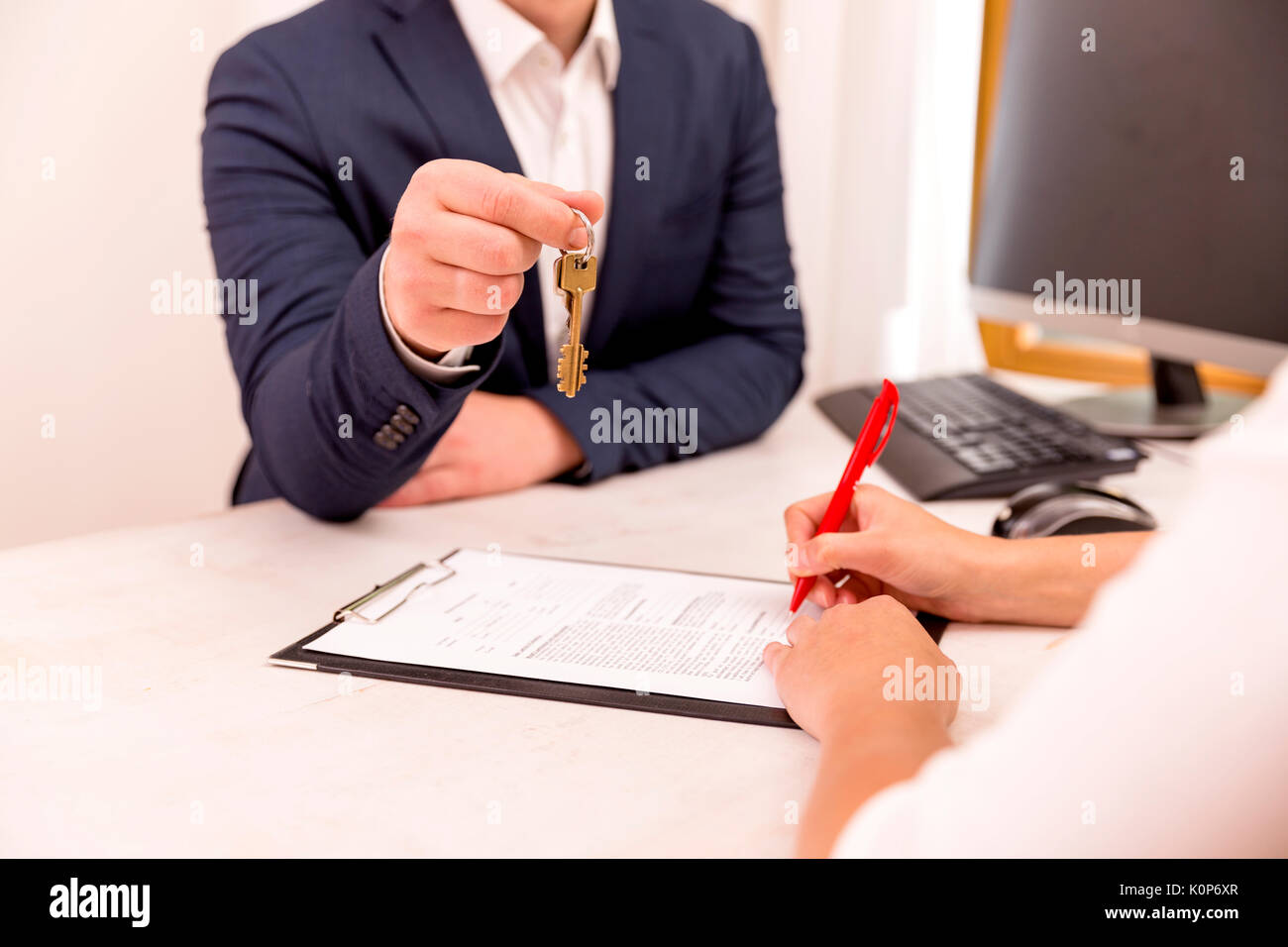 Real estate agent holding house key to his client after signing ...