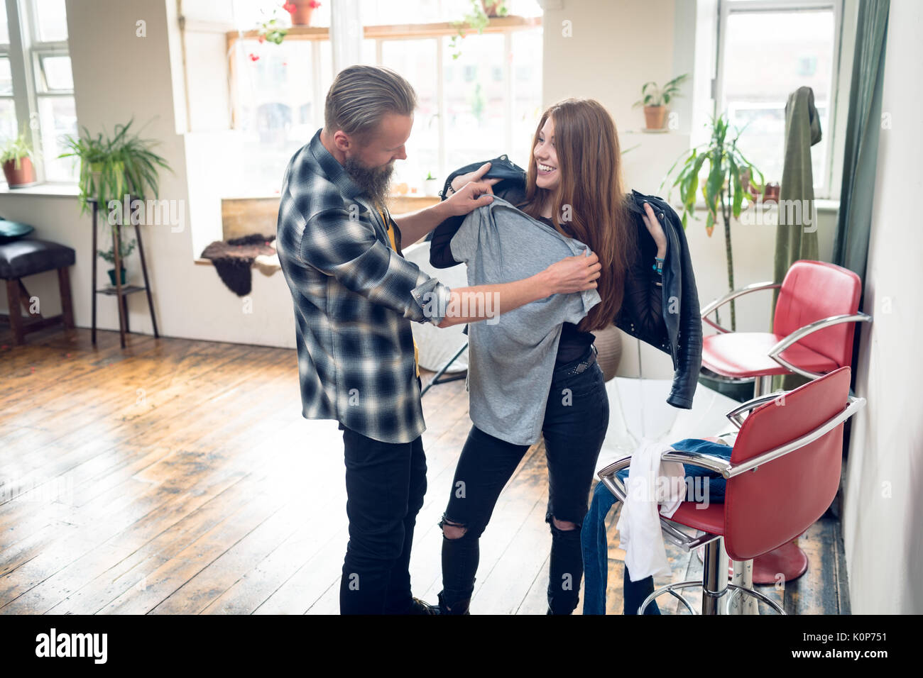 Side view of photographer trying t shirt on woman while standing in ...
