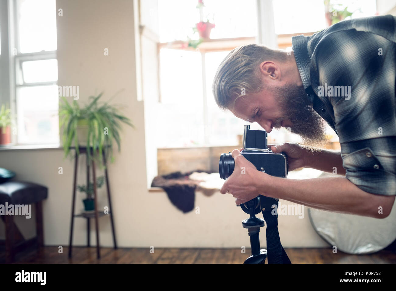 Side view of male photographer photographing throuch camera in studio ...