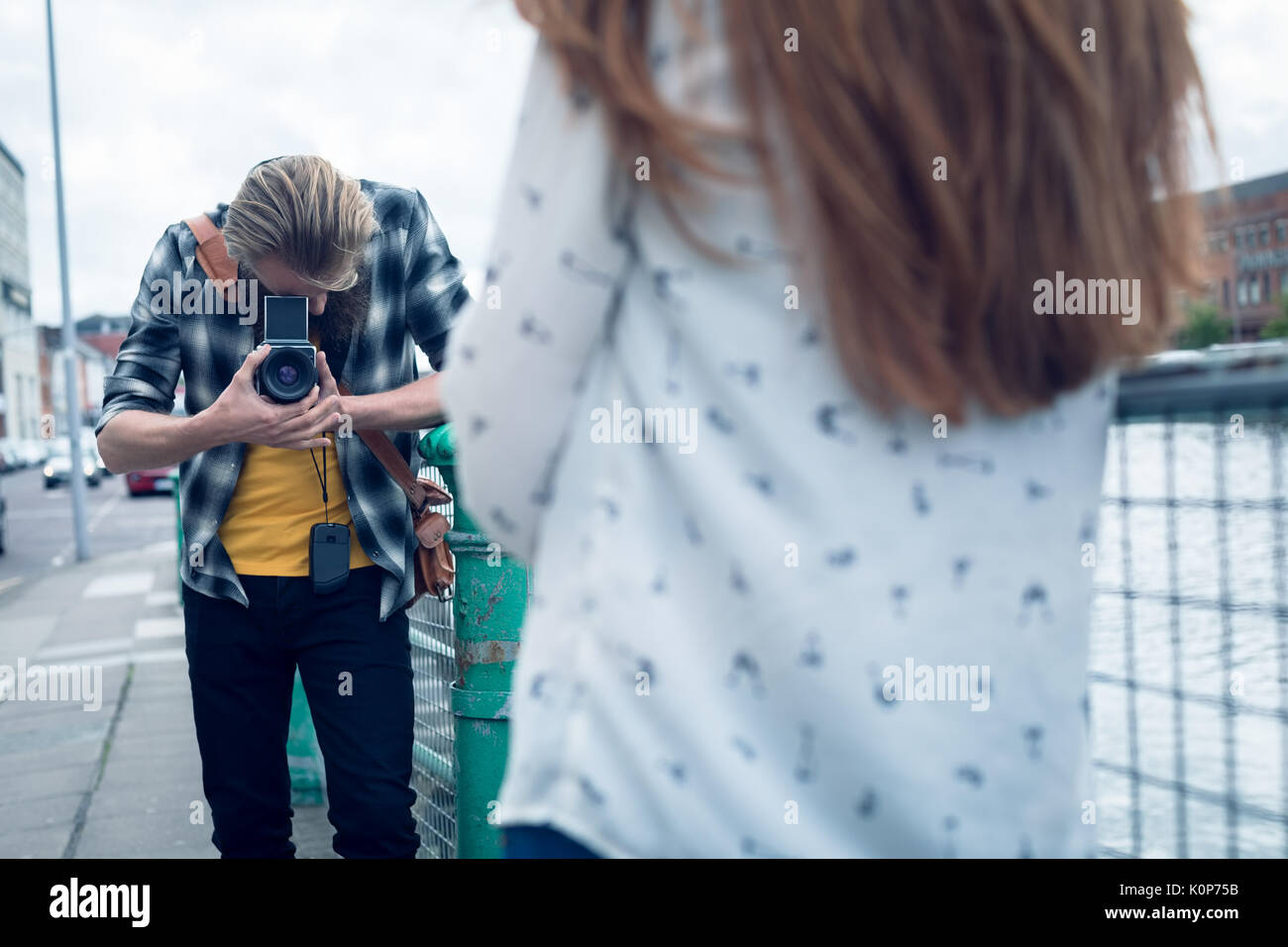 Photographer photographing fashion model while standing on footpath in ...