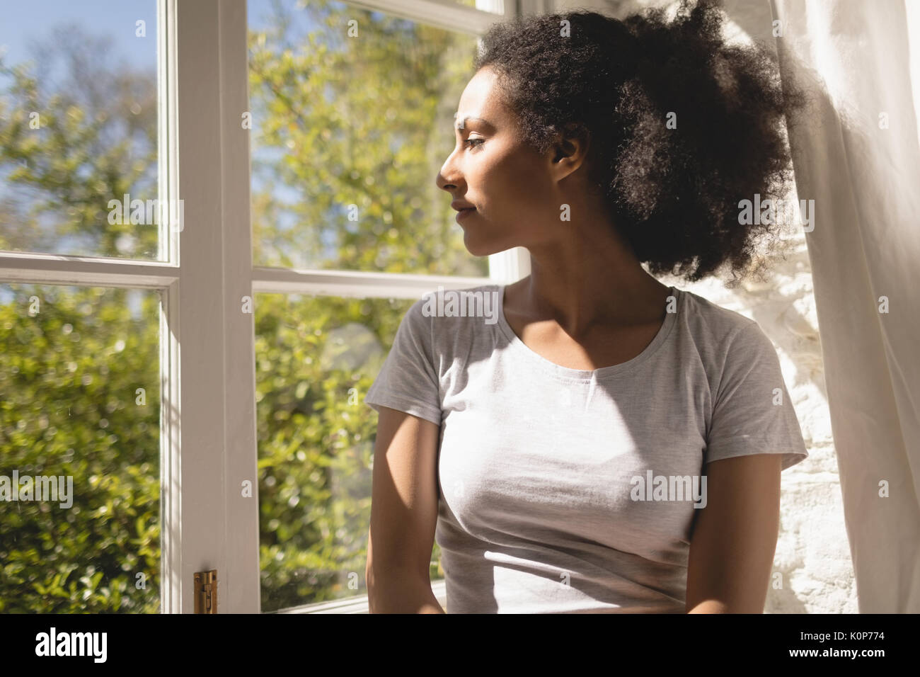 Woman sitting at window sill at home Stock Photo - Alamy