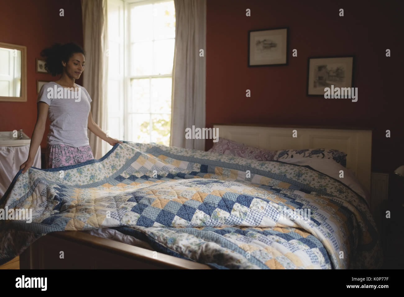 Woman making bed in bedroom at home Stock Photo - Alamy