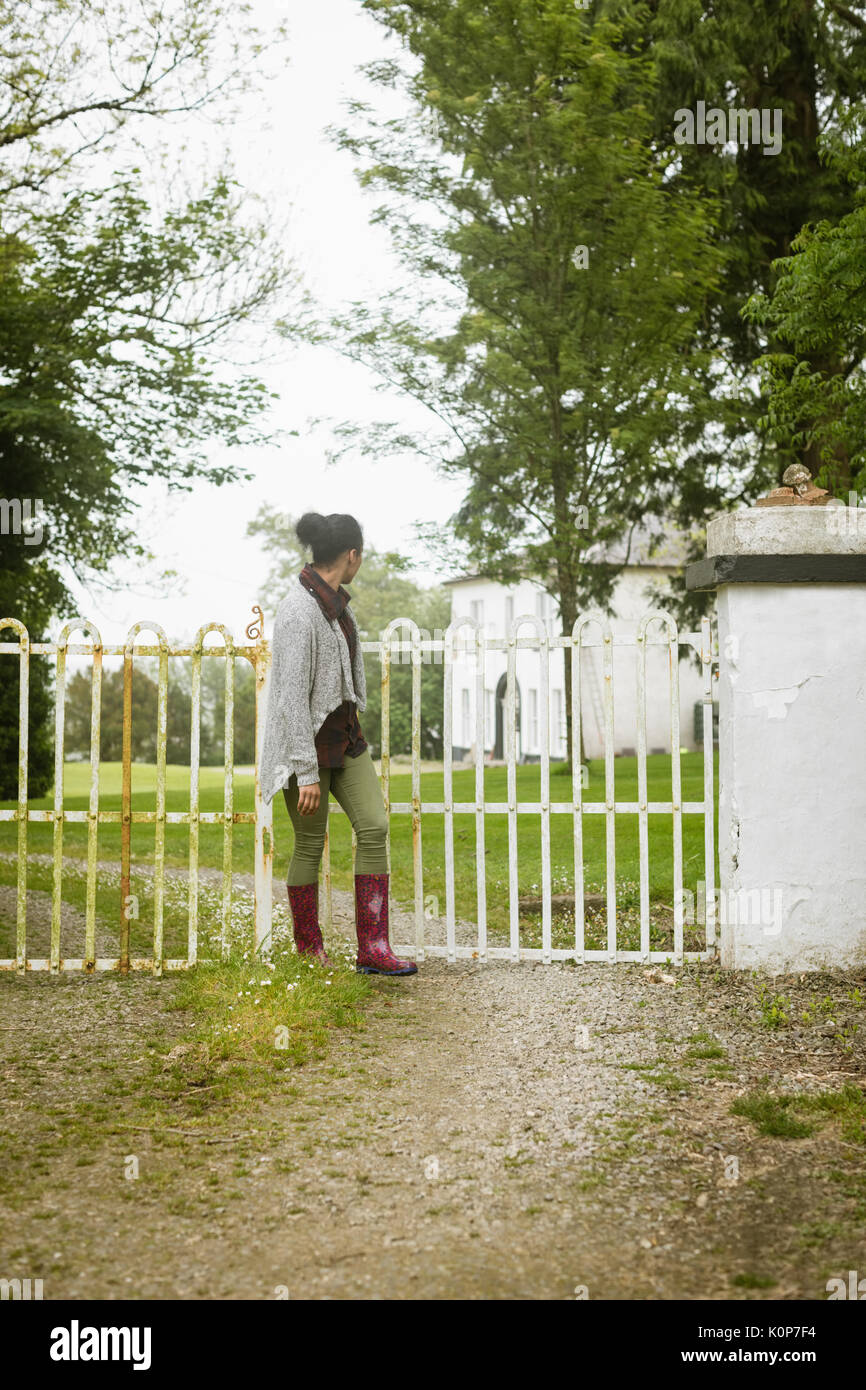 Thoughtful woman standing near gate Stock Photo - Alamy
