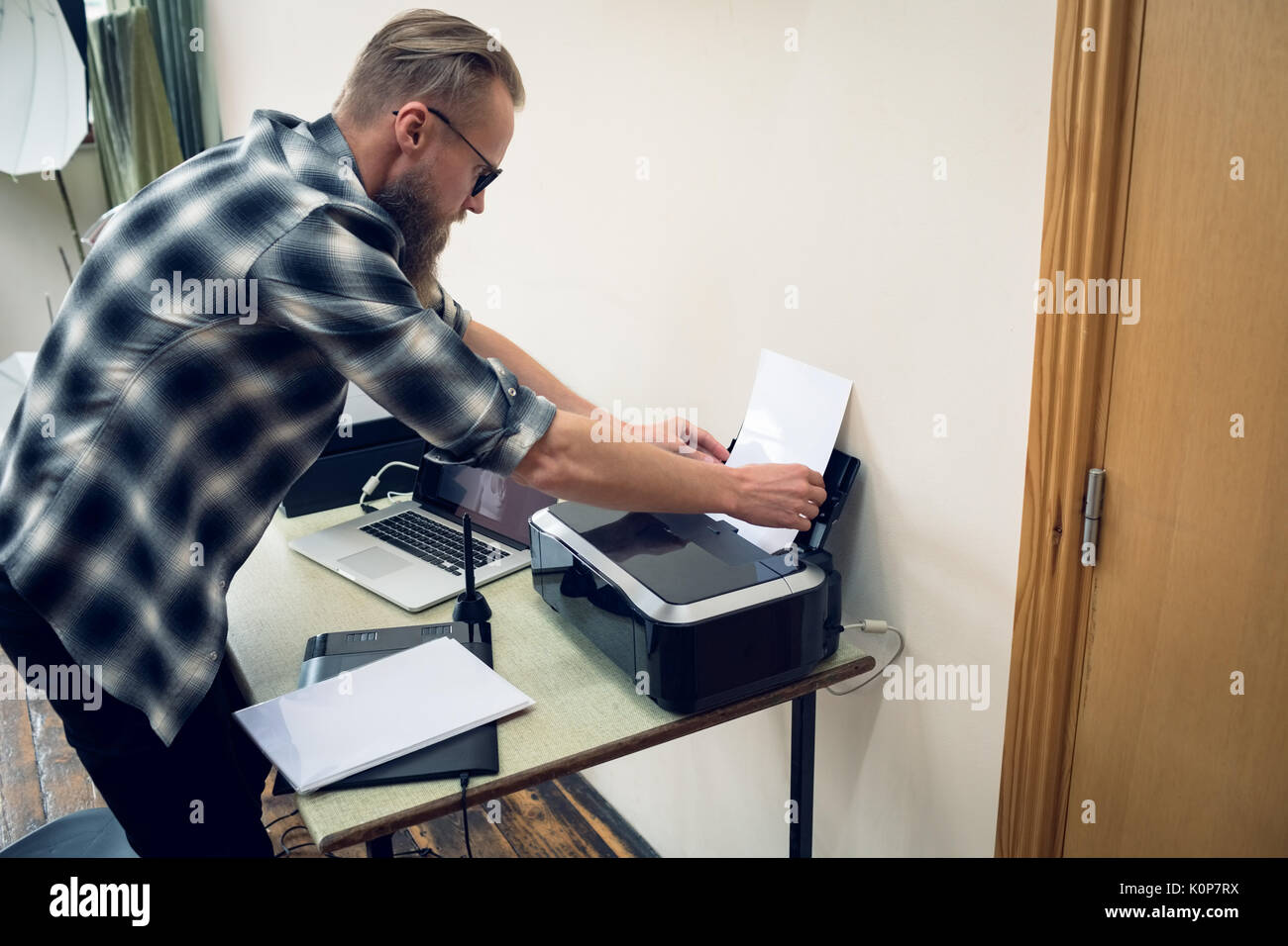 Side view of photographer putting paper in printer while working at ...