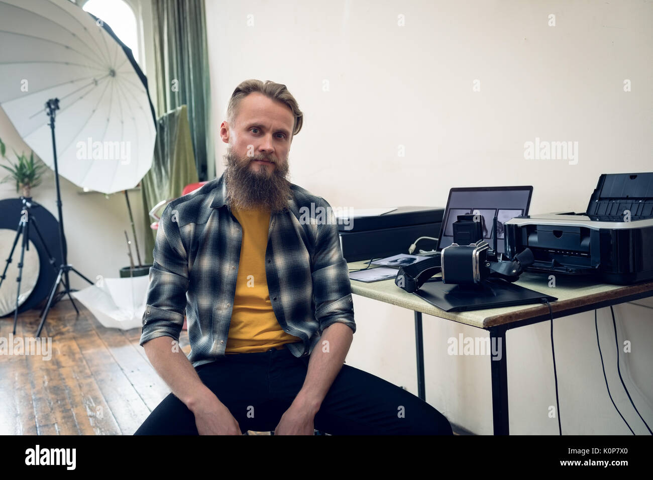 Portrait of photographer sitting by table in studio Stock Photo - Alamy