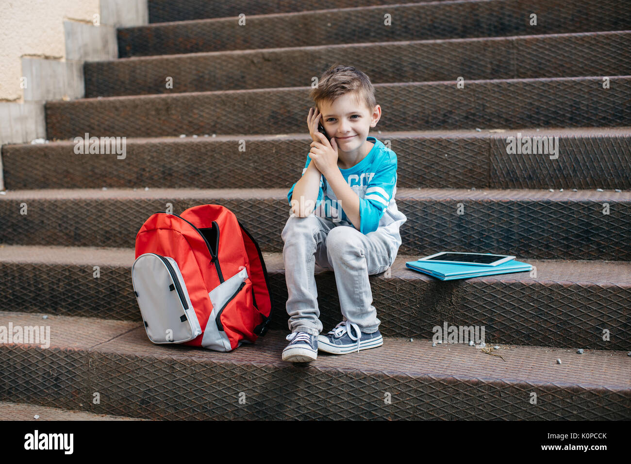 Smiling child making a phone call outside a school Stock Photo - Alamy
