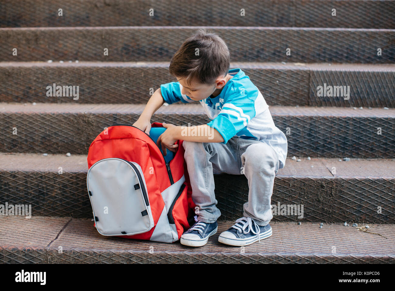 Little student on his first day of school checking books inside his ...