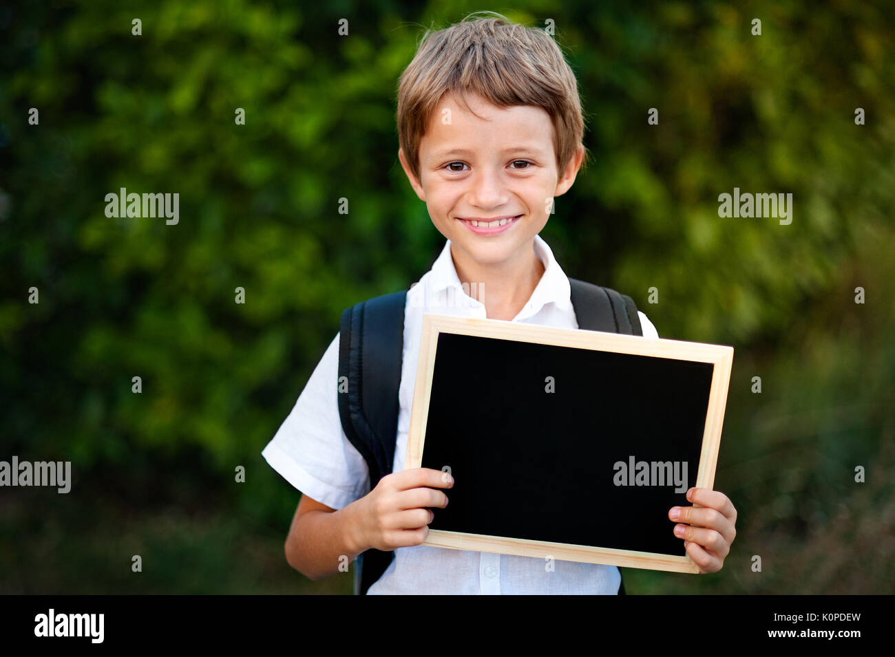 Cute caucasian school child hold a blank chalkboard for education ...