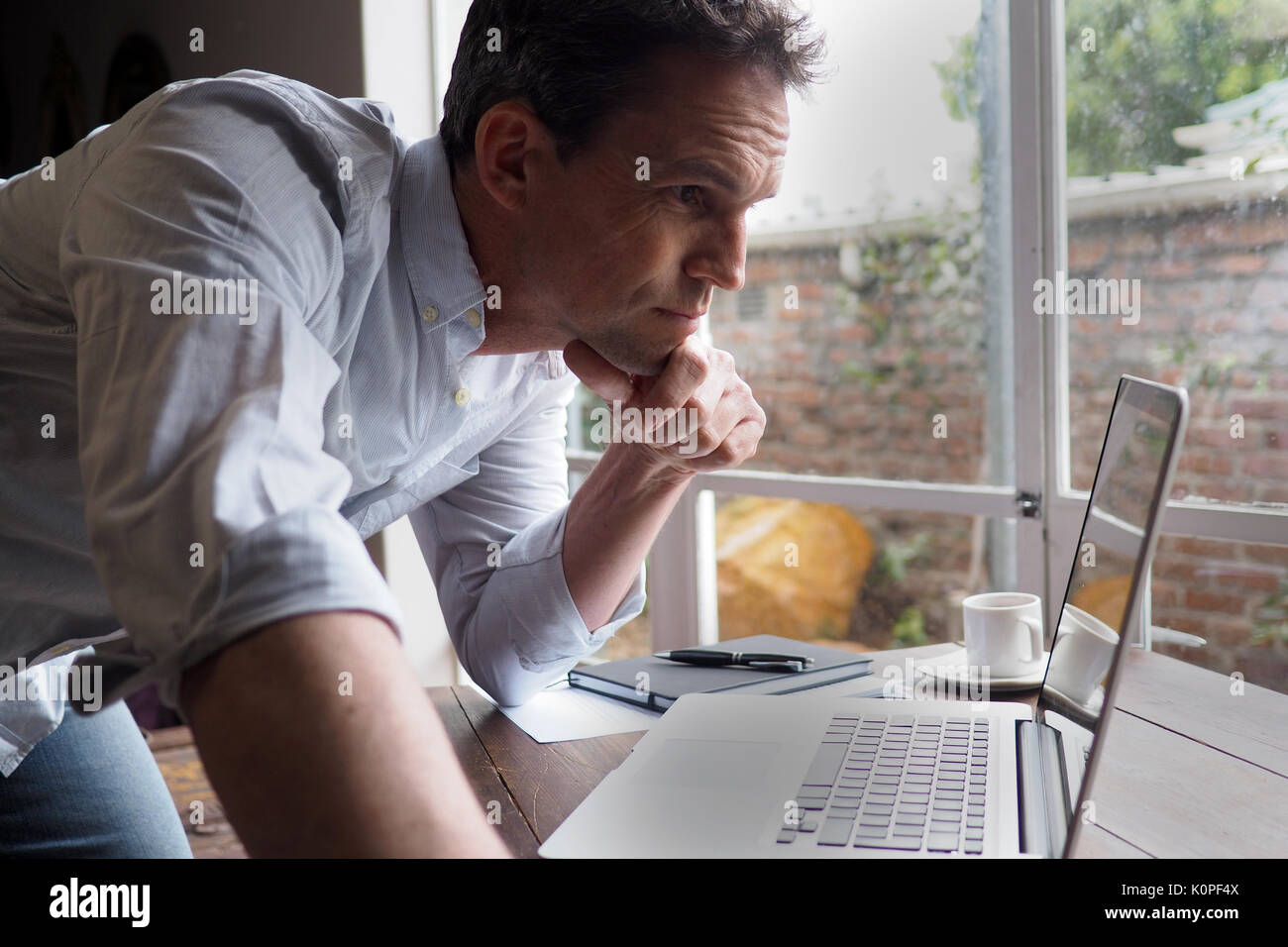 Man looking at computer, standing, in home office Stock Photo - Alamy