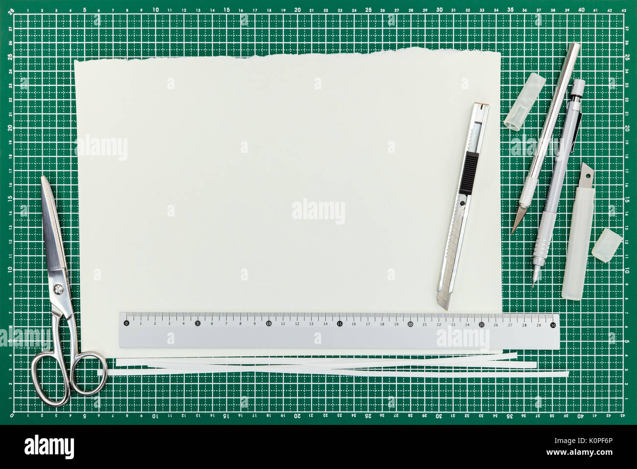 cutter with blades, scissors, pencil, ruler and empty paper sheet on ...