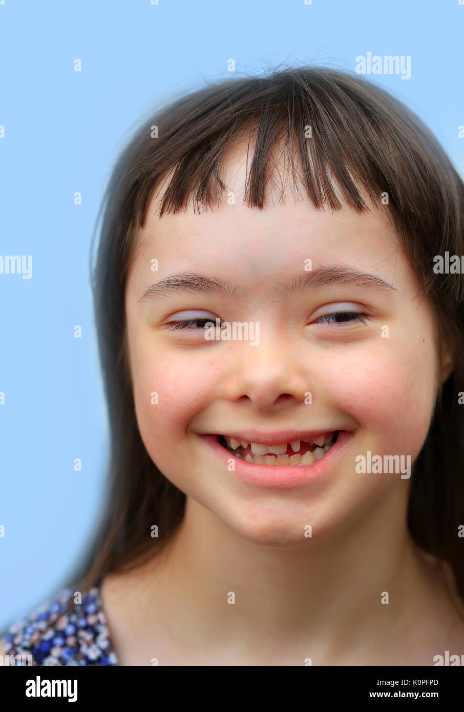Cute smiling down syndrome girl on the brown background Stock Photo - Alamy