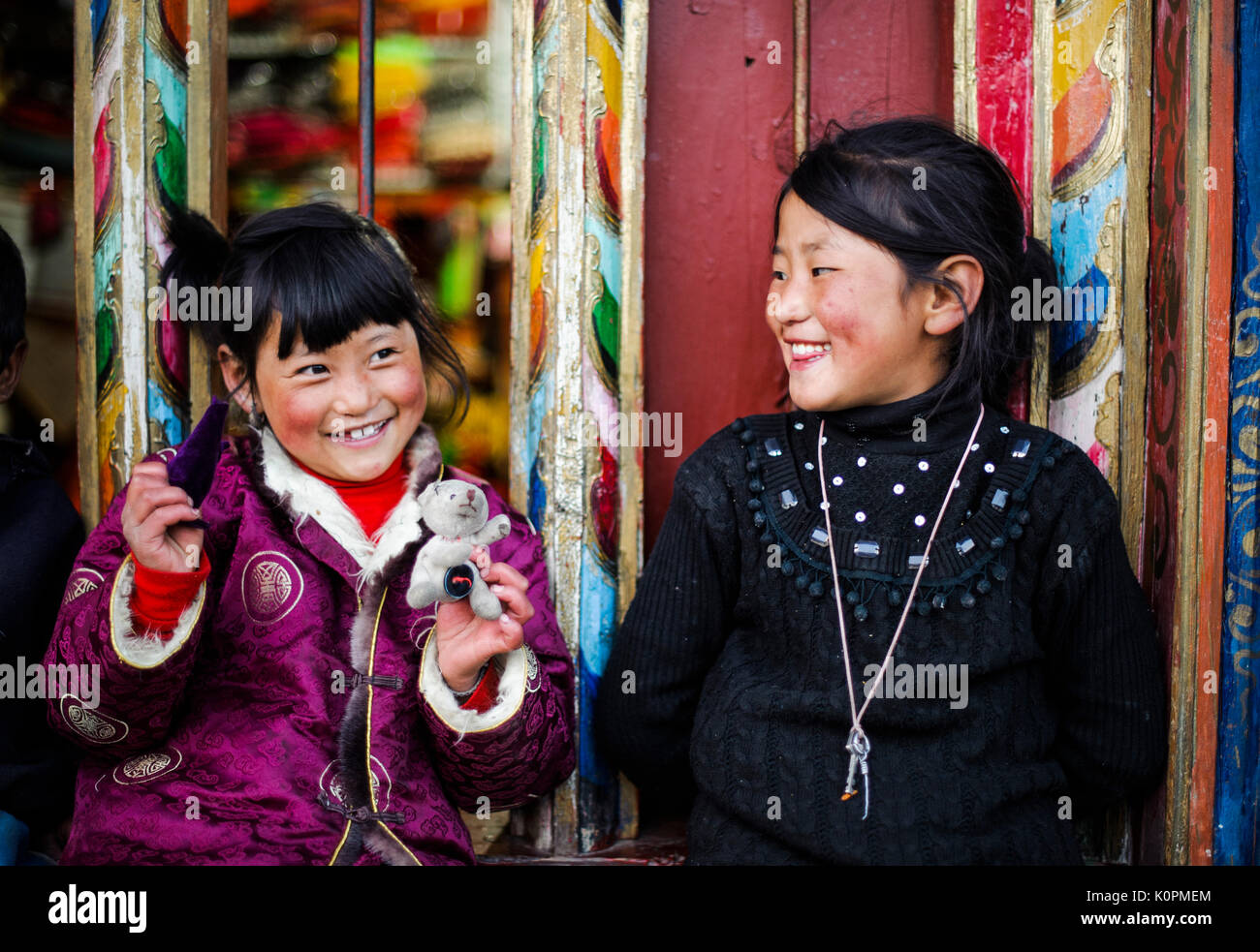 Two Tibetan kids playing at the front of a typical Tibetan decorated ...