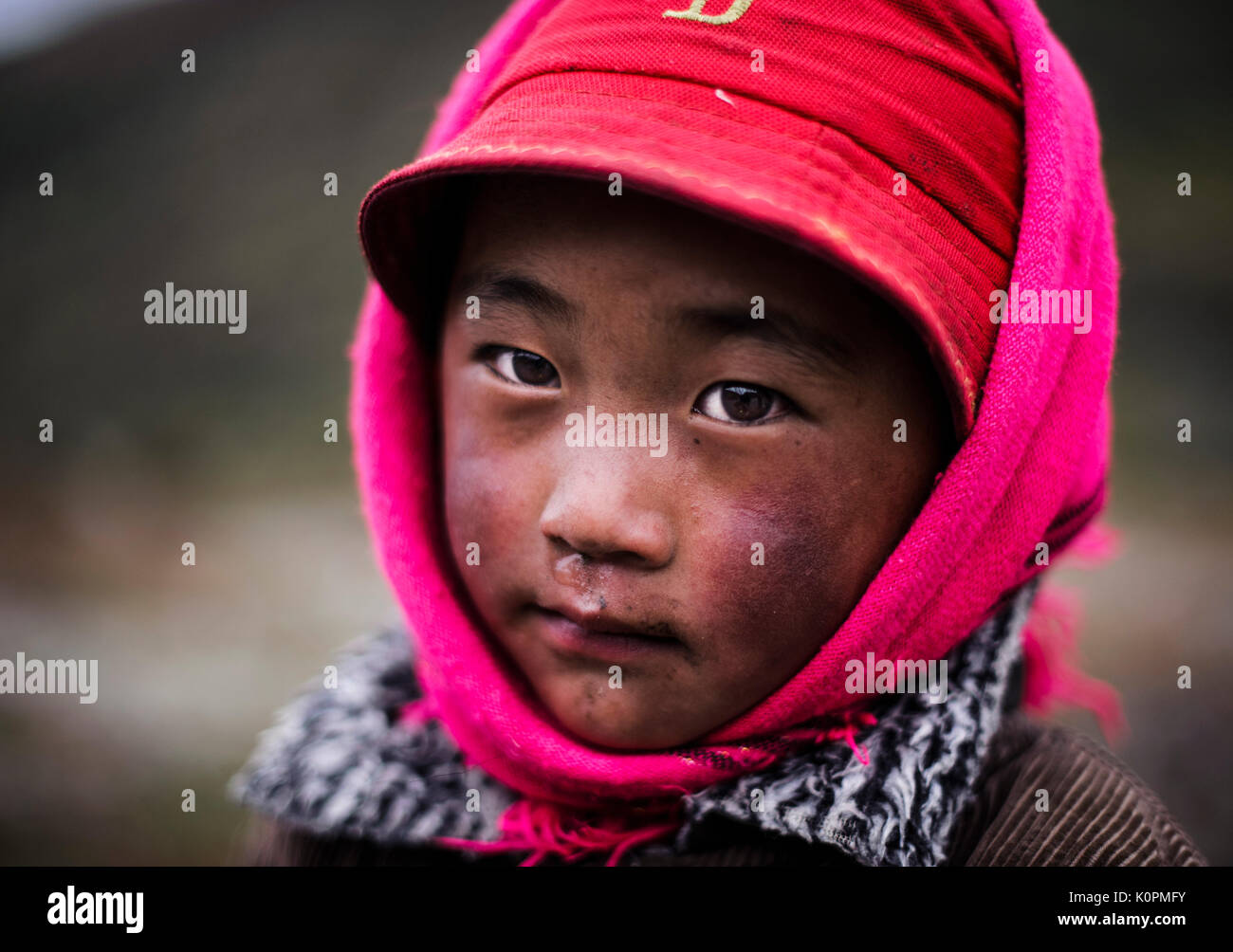 Portrait of a Tibetan kid out in the cold with his cheeks reddened by ...