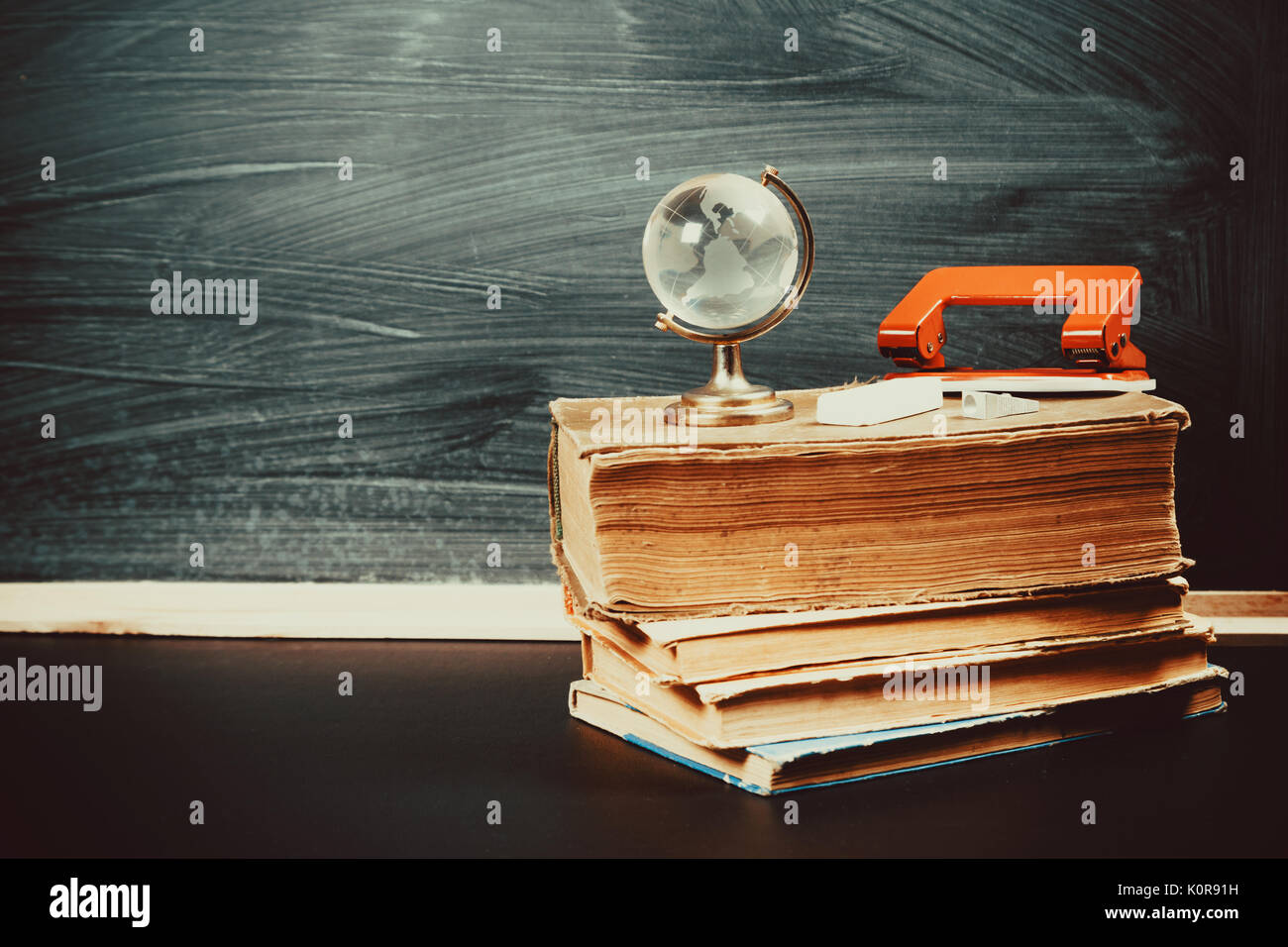 Old blackboard with chalk, books, a globe and a pencil. A beautiful ...