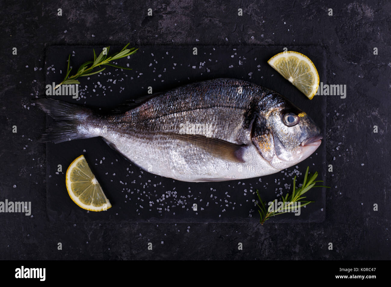 Sea bream on slate board with rosemary hi-res stock photography and ...
