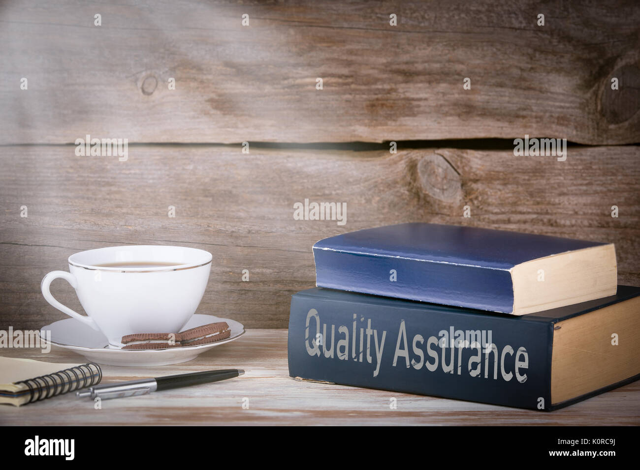 Quality Assurance concept. Stack of books on wooden desk Stock Photo ...