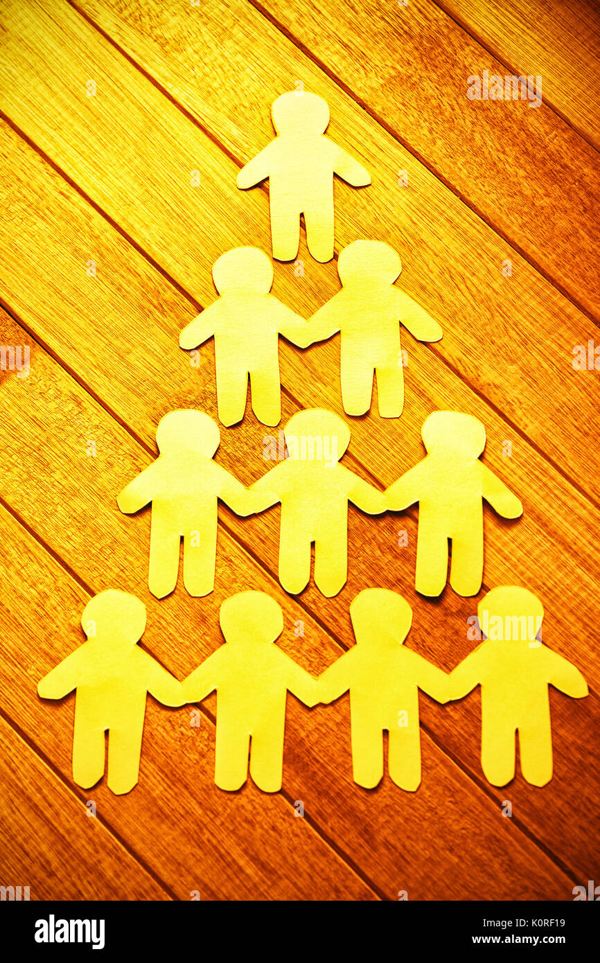 High angle view of paper cut out figures forming human pyramid on table ...