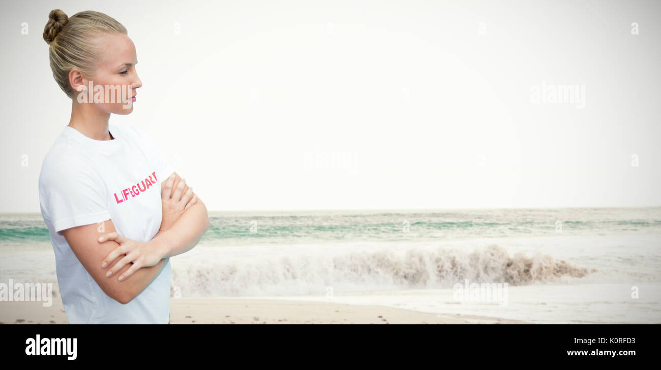 side view of female lifeguard with arms crossed against scenic view of ...