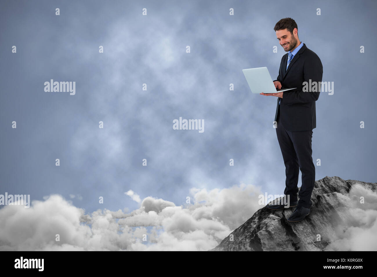 Businessman standing while using laptop computer against dark ...