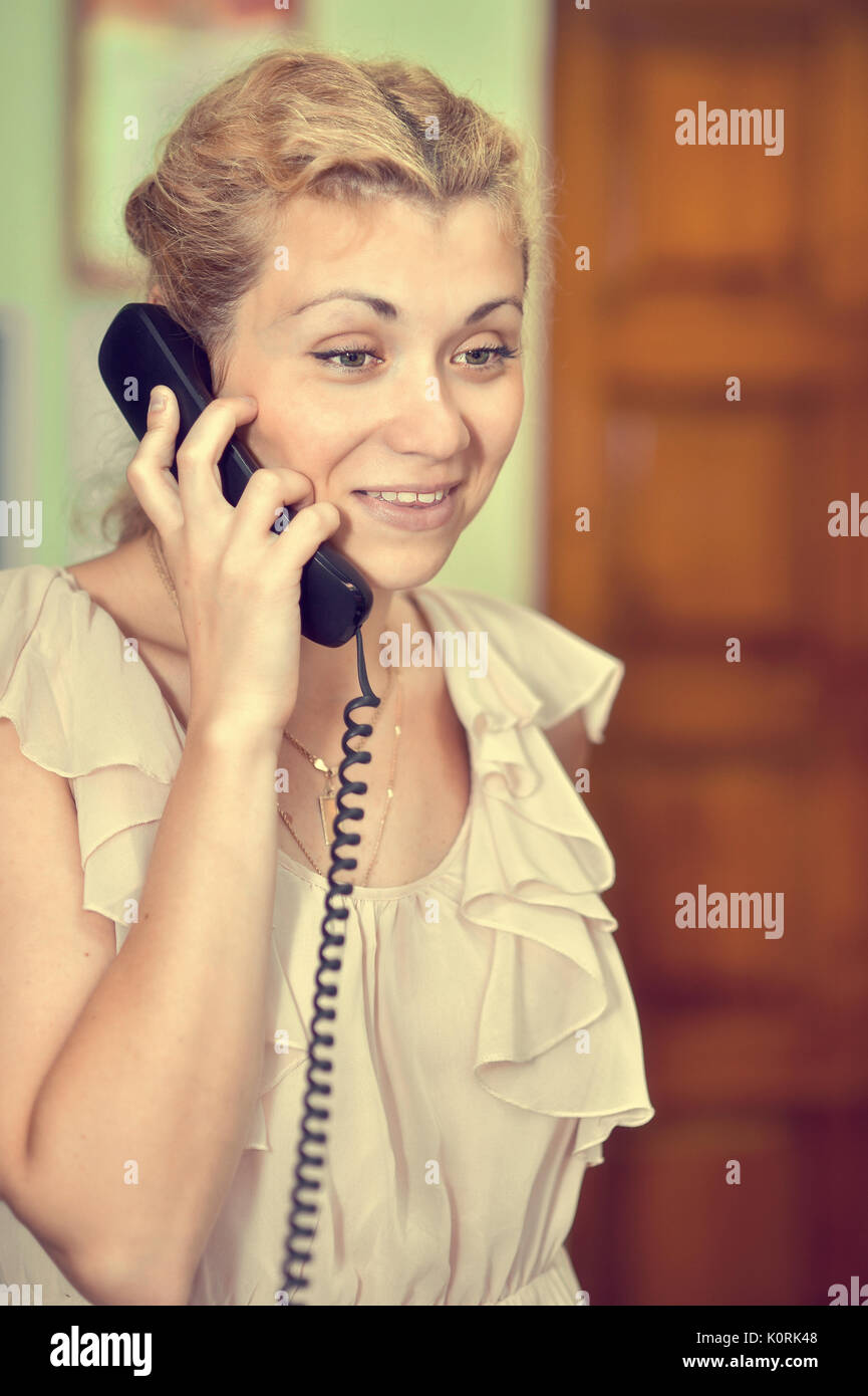 Smiling girl talking on wire telephone Stock Photo - Alamy