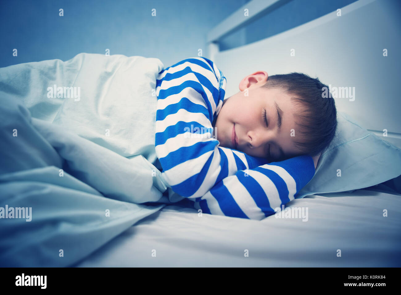 Boy sleeping in bed in pajamas Stock Photo - Alamy