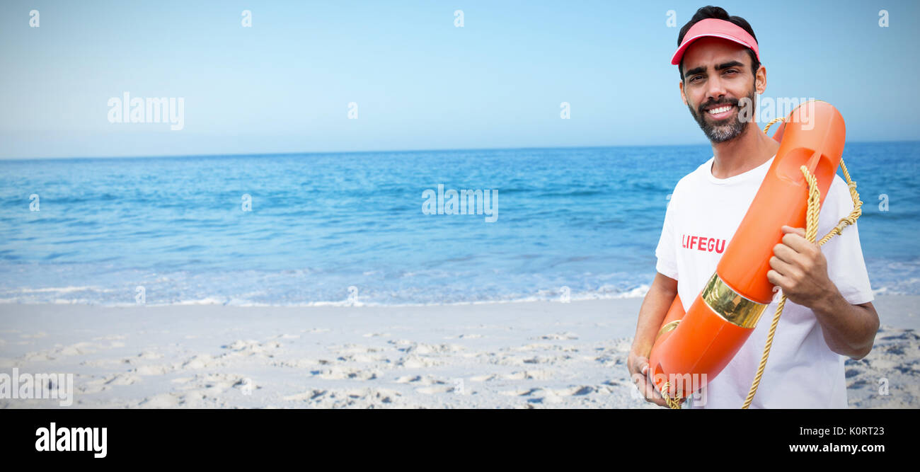 Portrait of male lifeguard holding life belt against beach against ...