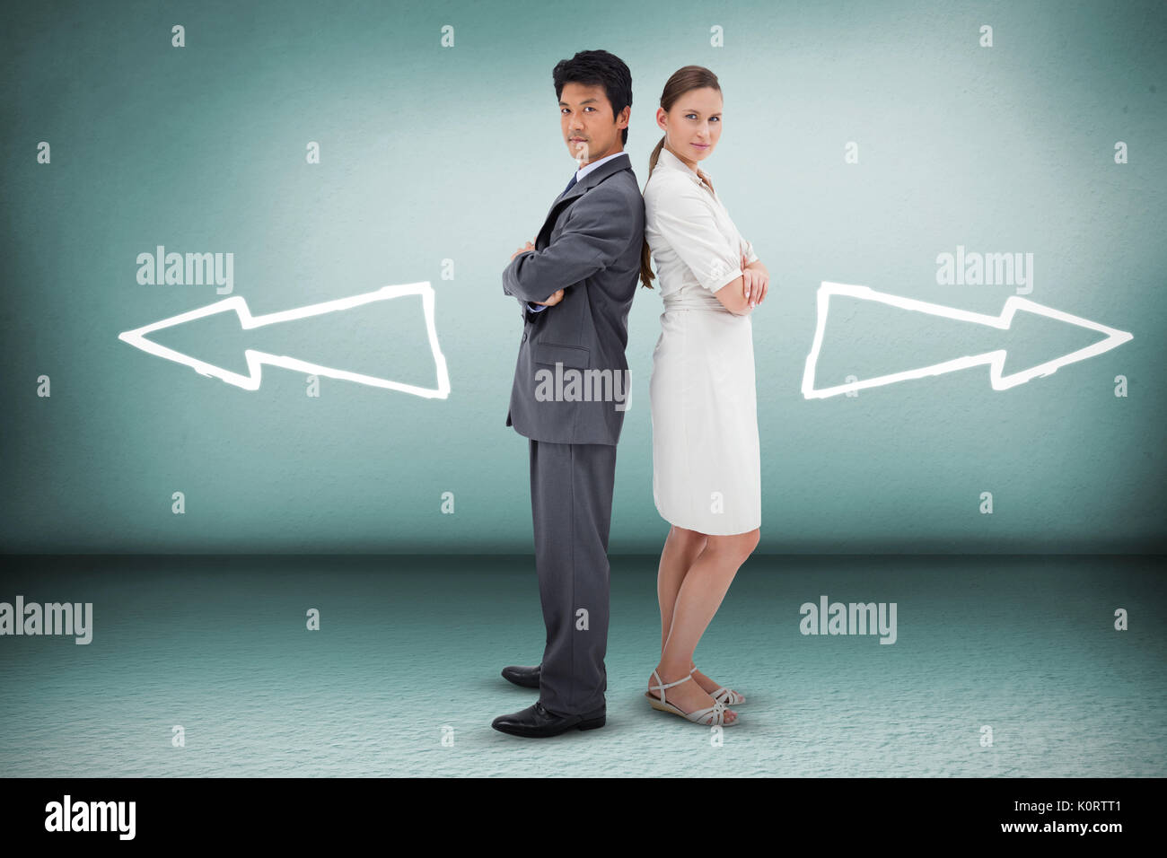 Portrait of business people standing back-to-back against grey room ...
