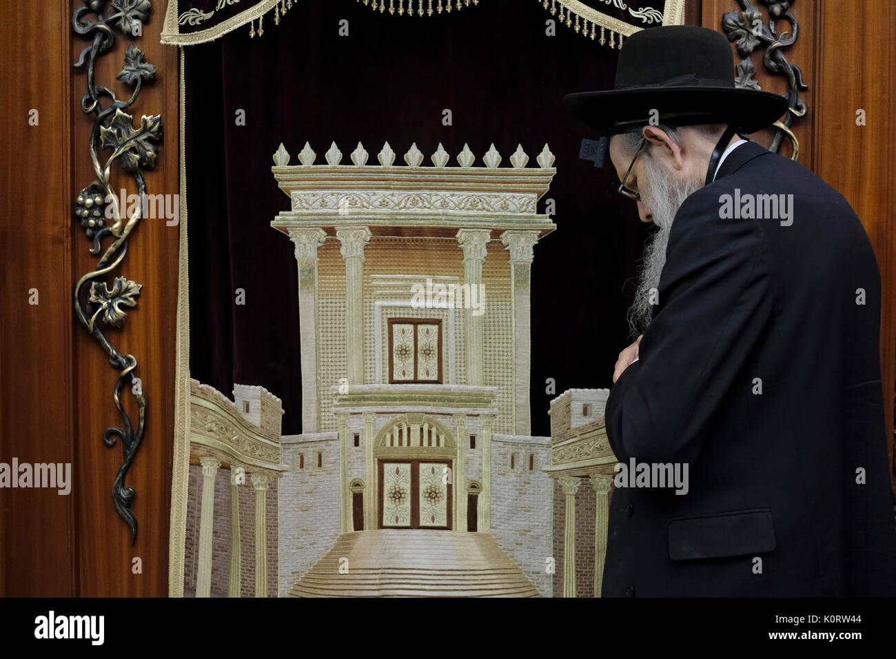 A Jewish worshiper praying next to a Torah Ark closet which contains ...