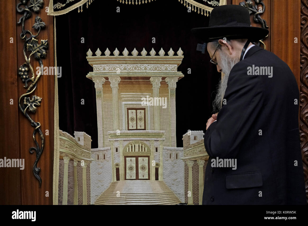 A Jewish worshiper praying next to a Torah Ark closet which contains ...