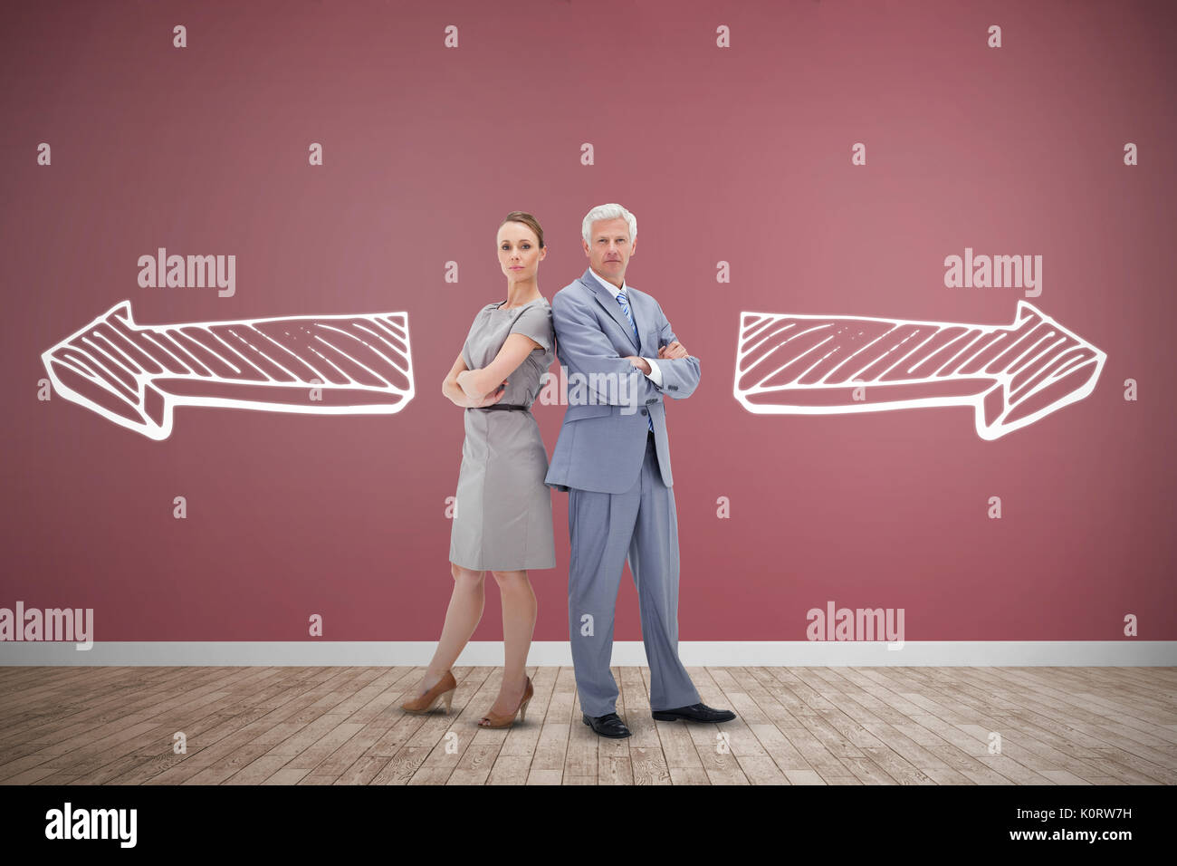 Serious businessman standing back to back with a woman against room ...