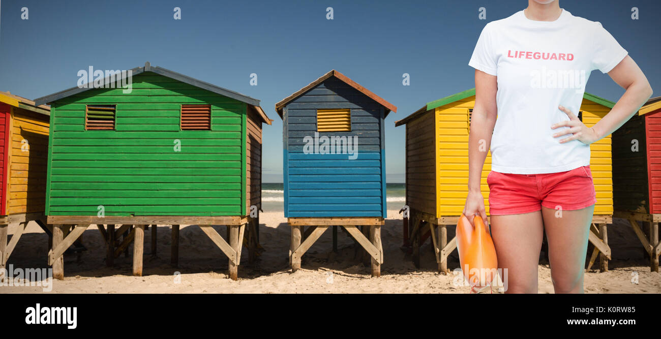 Mid section of female lifeguard holding rescue buoy against colorful ...