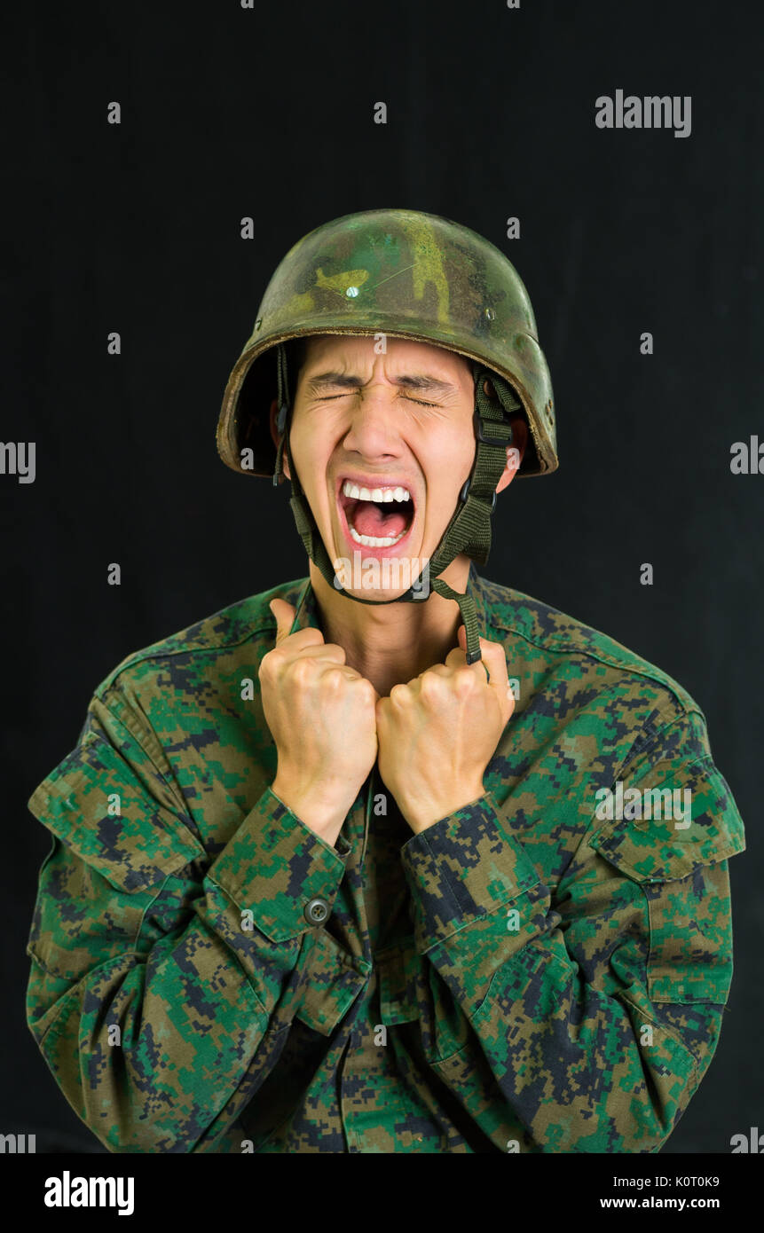 Handsome young soldier wearing uniform suffering from stress, screaming ...