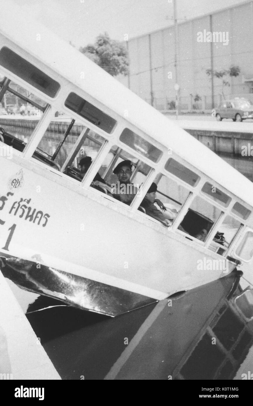 Bus hanging over a bridge, in a city setting, with three Vietnamese ...