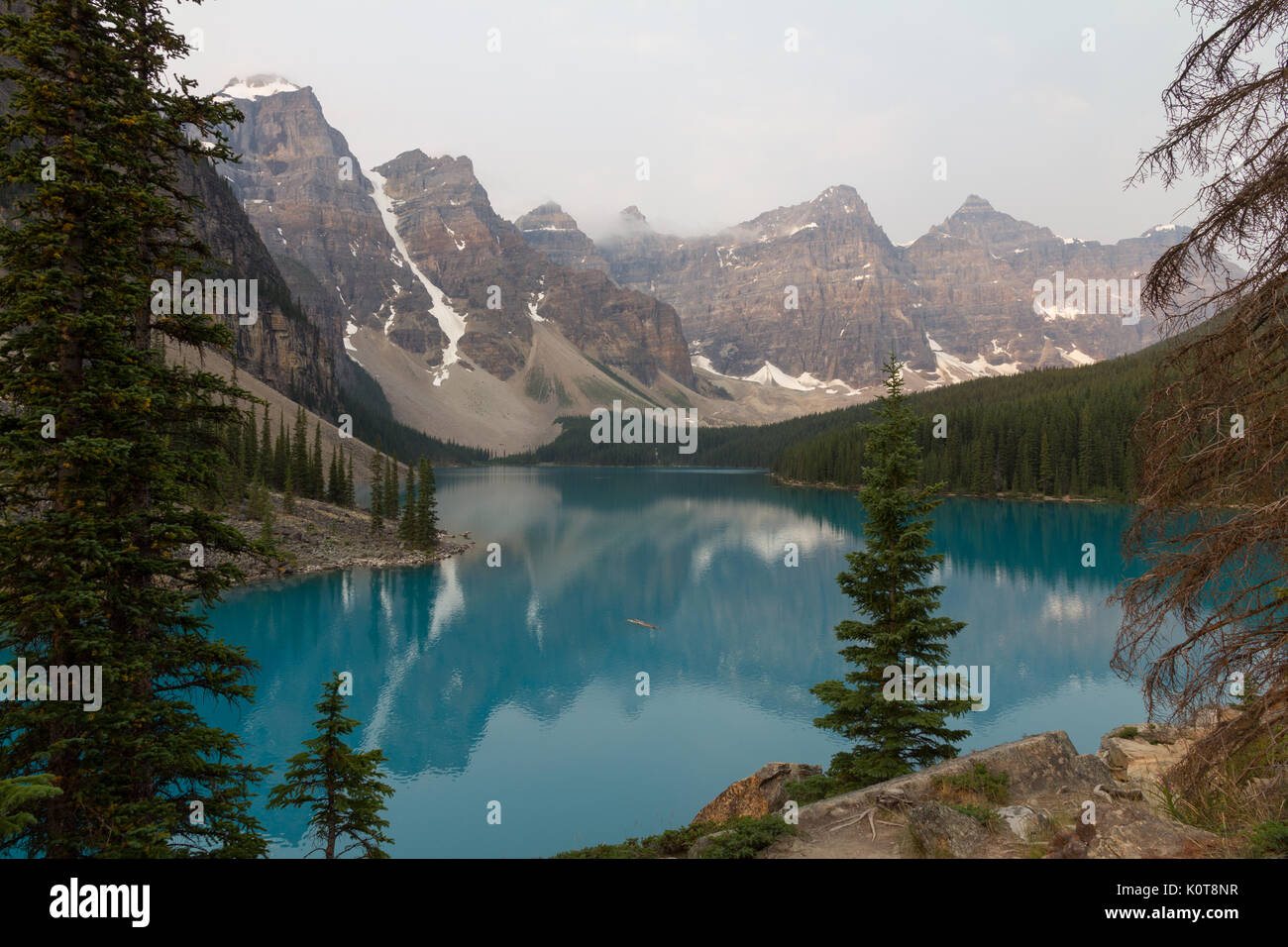 Early morning clouds and wildfire smoke reflect over Moraine Lake in ...