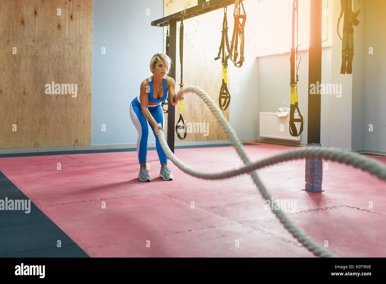 Woman with battle ropes exercise in the fitness gym. Young female ...
