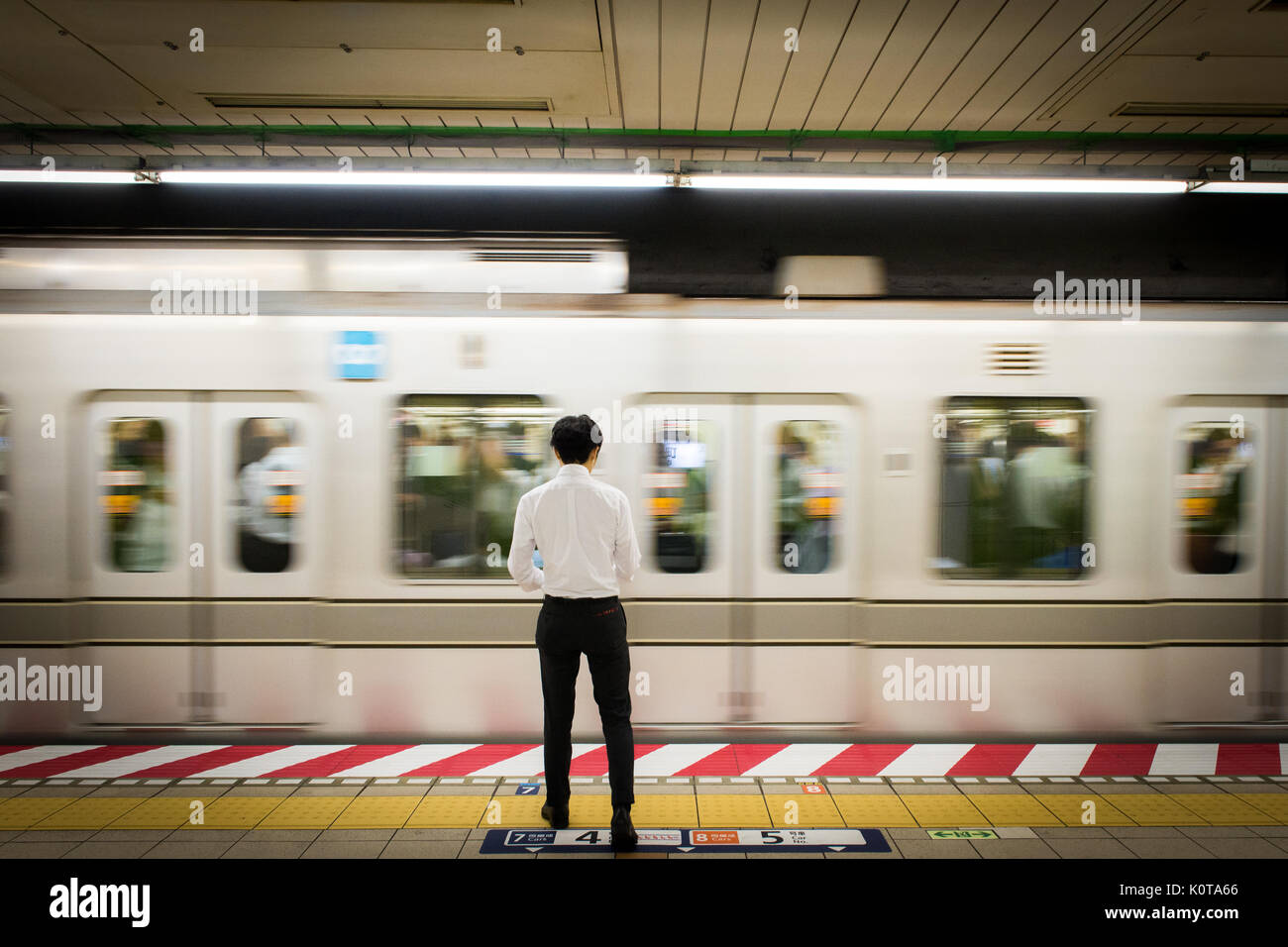 Electric train moving through train station and one man standing Stock ...