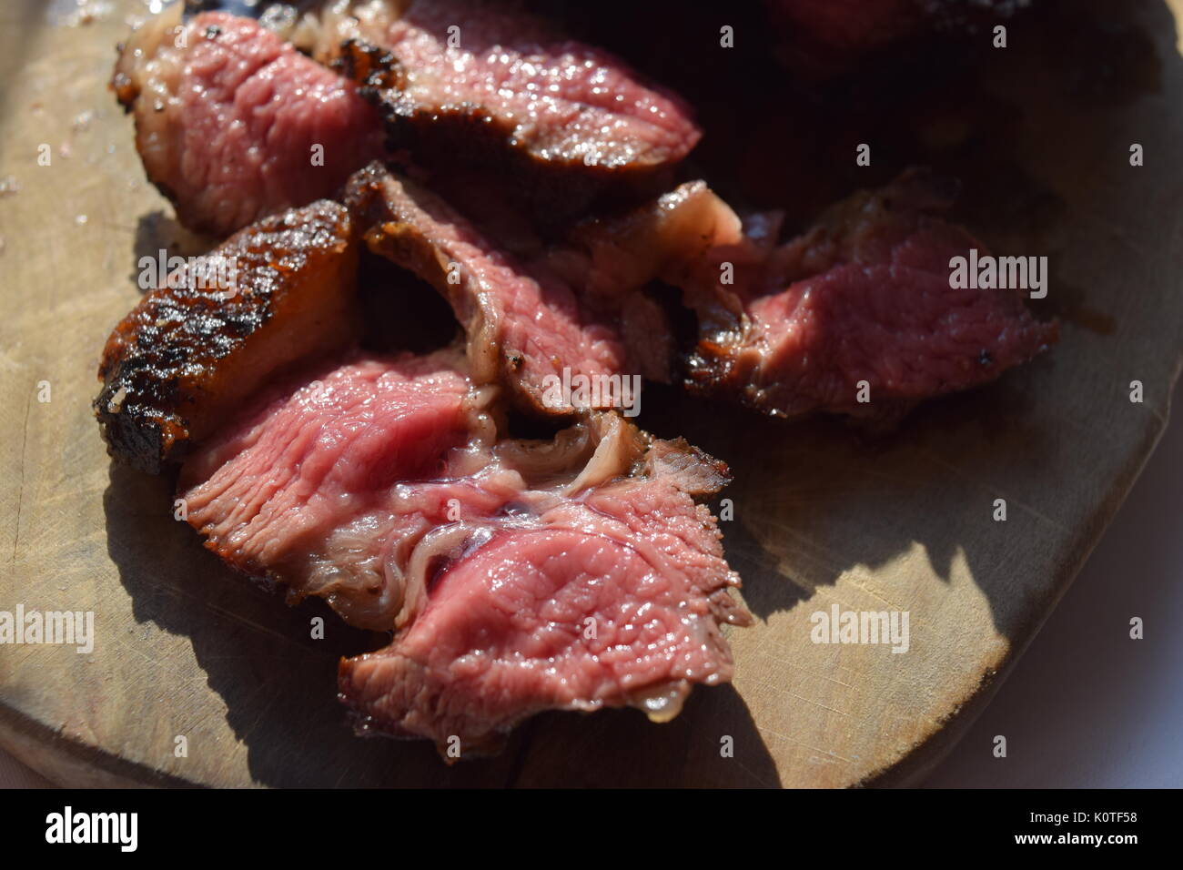 Close up of medium rare meat on a wooden boar Stock Photo - Alamy