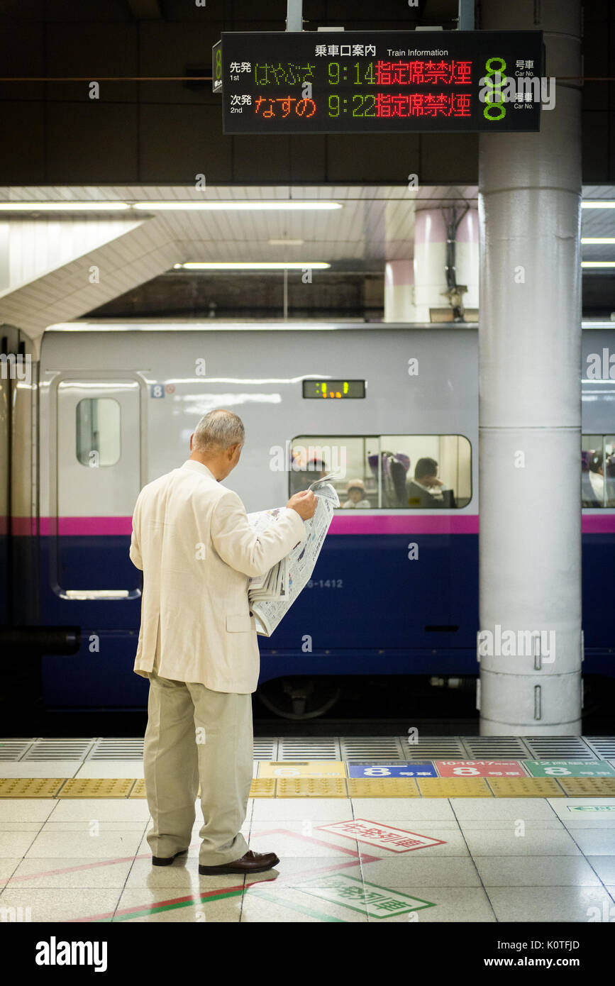 Man standing on train platform reading a newspaper Stock Photo - Alamy