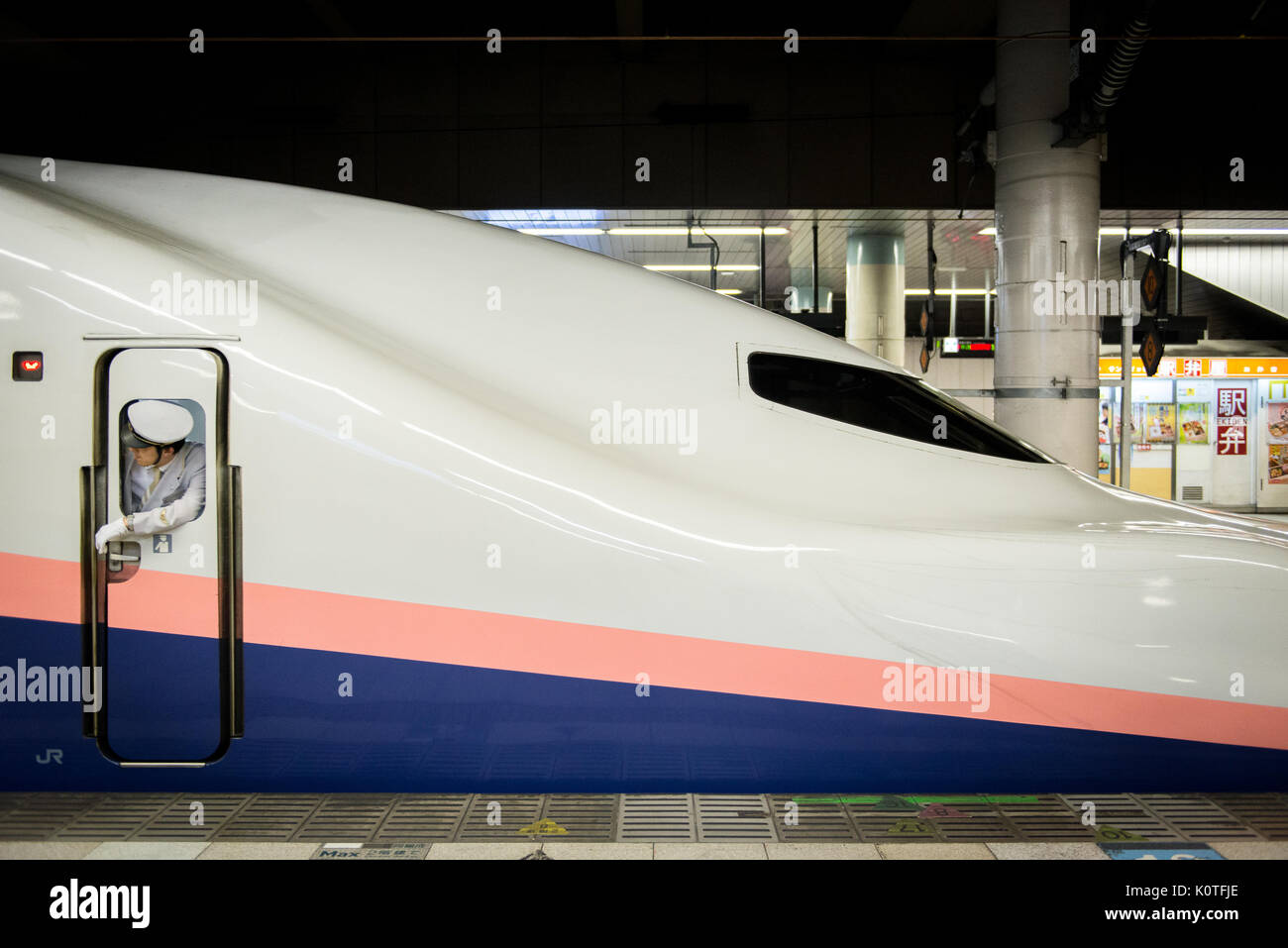 Bullet train stopped at station with operator looking out the window ...
