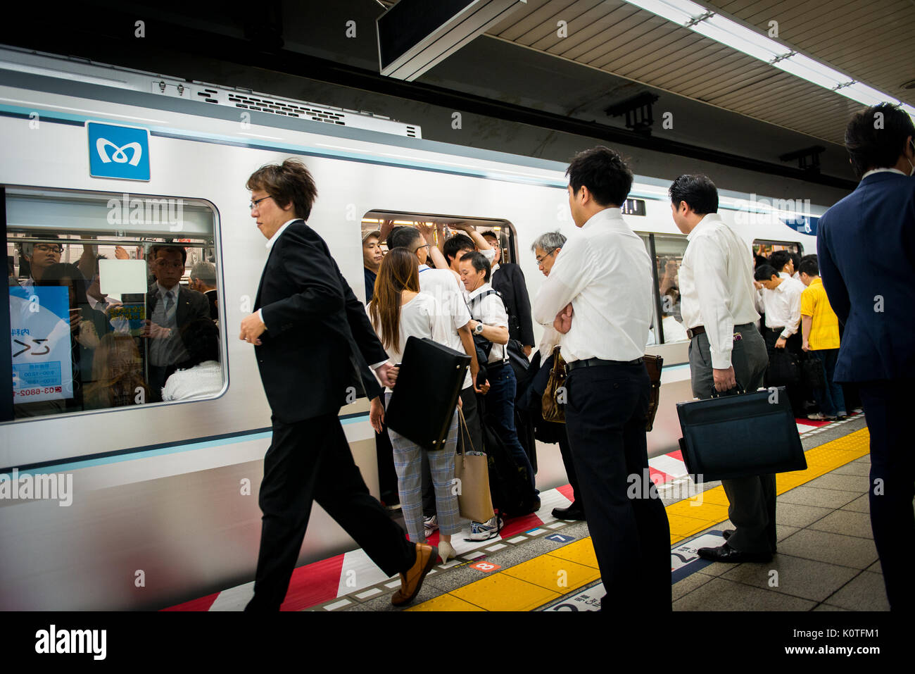 Commuters in Tokyo waiting for subway train Stock Photo - Alamy