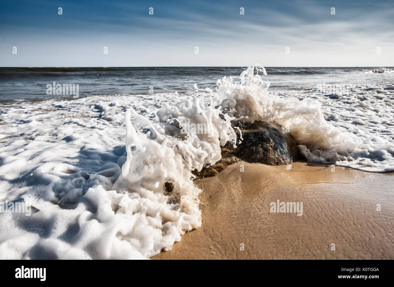 Wave splash rock on the sand beach Stock Photo - Alamy