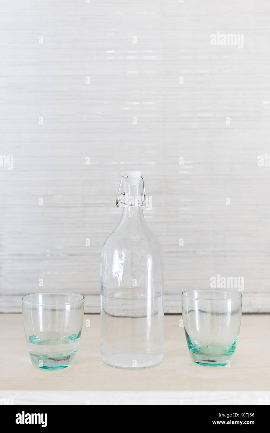One transparent glass bottle and two cup for water isolated on white ...