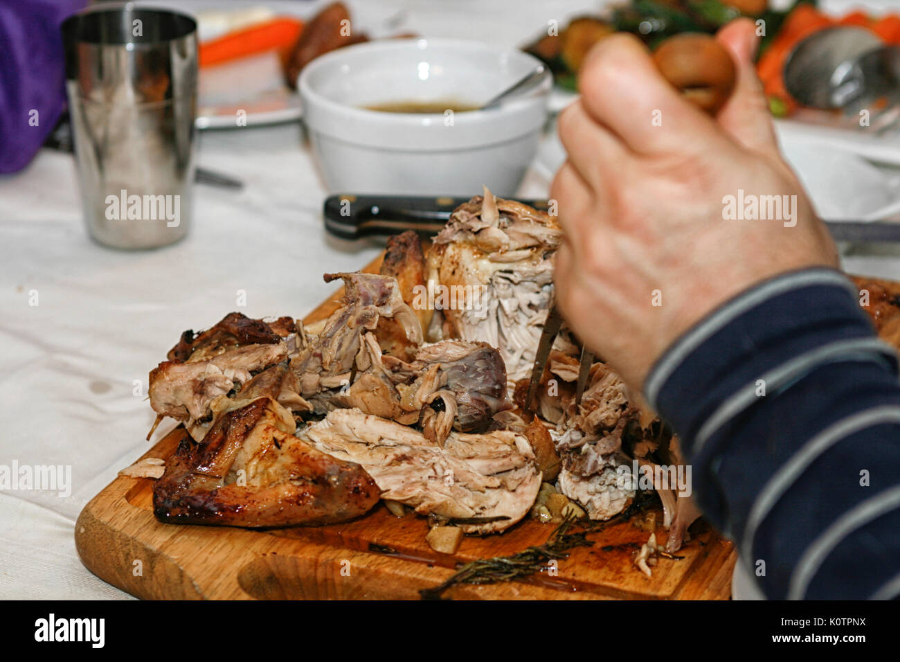 Man cutting cooked chicken on a board at the dinnertable Stock Photo ...