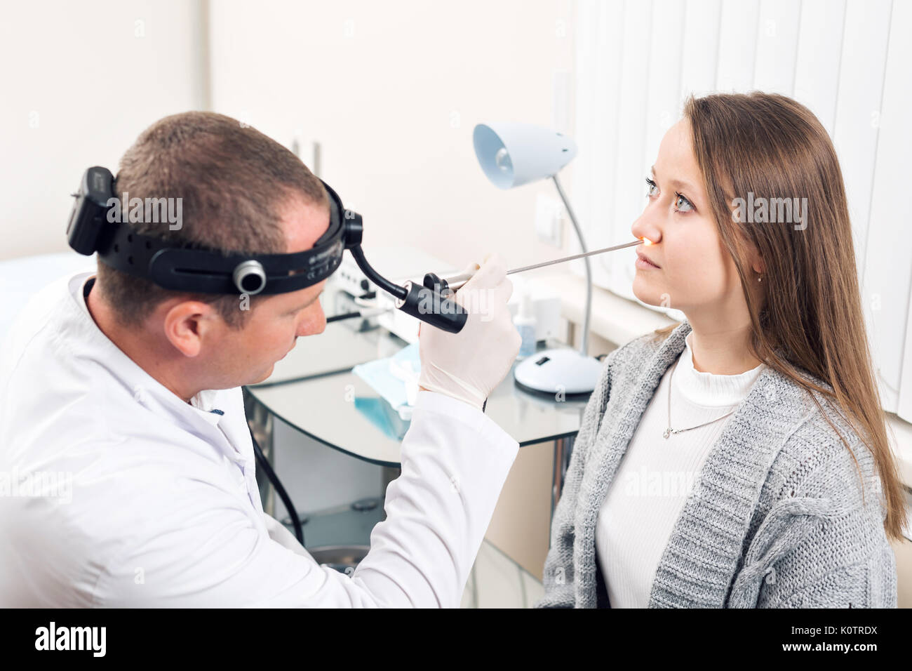 otolaryngologist. Very attentive medical worker looking at nose of his ...