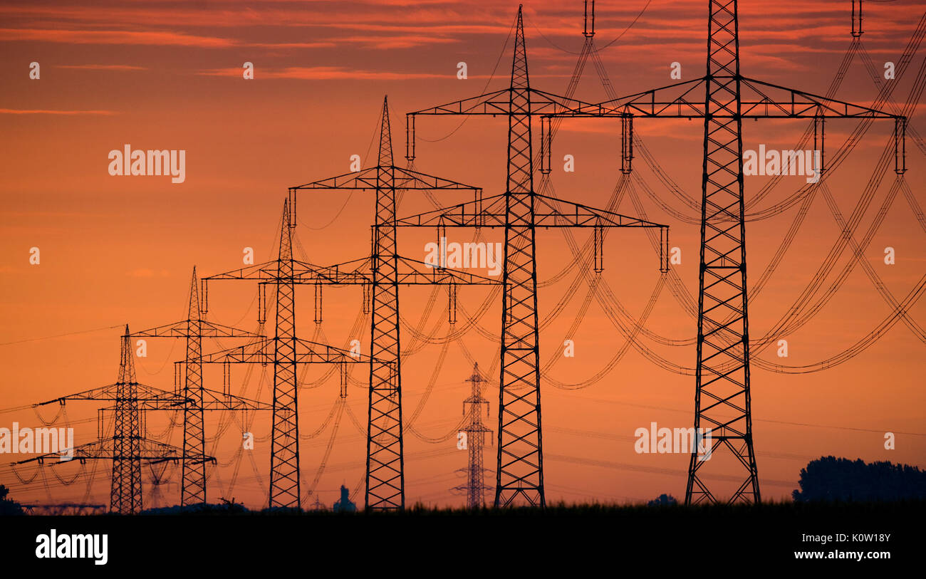 The rising sun flooding with a warm light the sky over high voltage ...